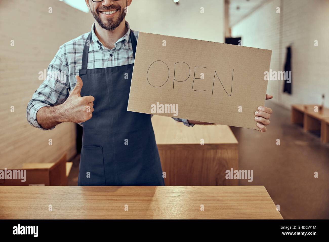 Joyful man holding open sign and giving thumbs up Stock Photo - Alamy