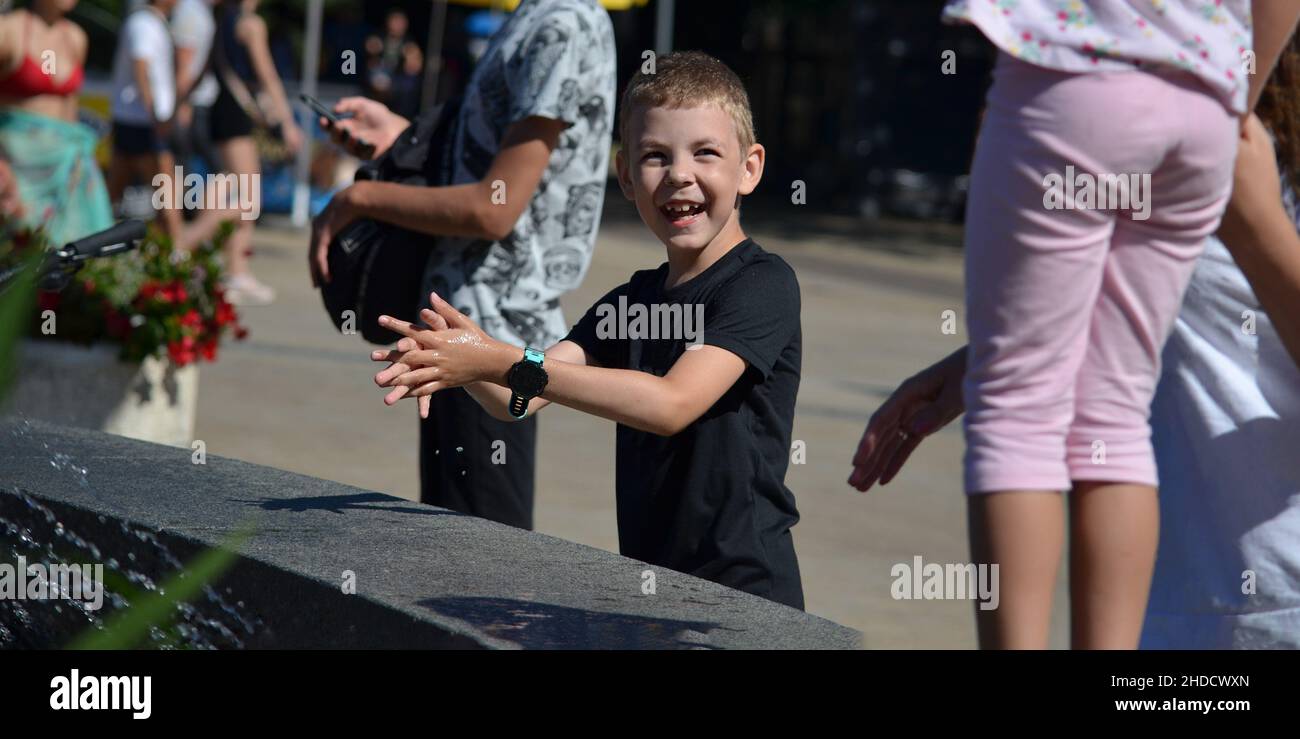 Children at the fountain. A boy of eight is having fun between the ...