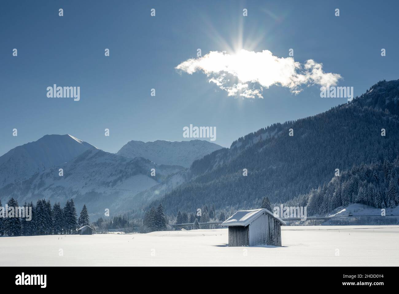 Winter shot of a barn in the snowy field, mountains in the background ...