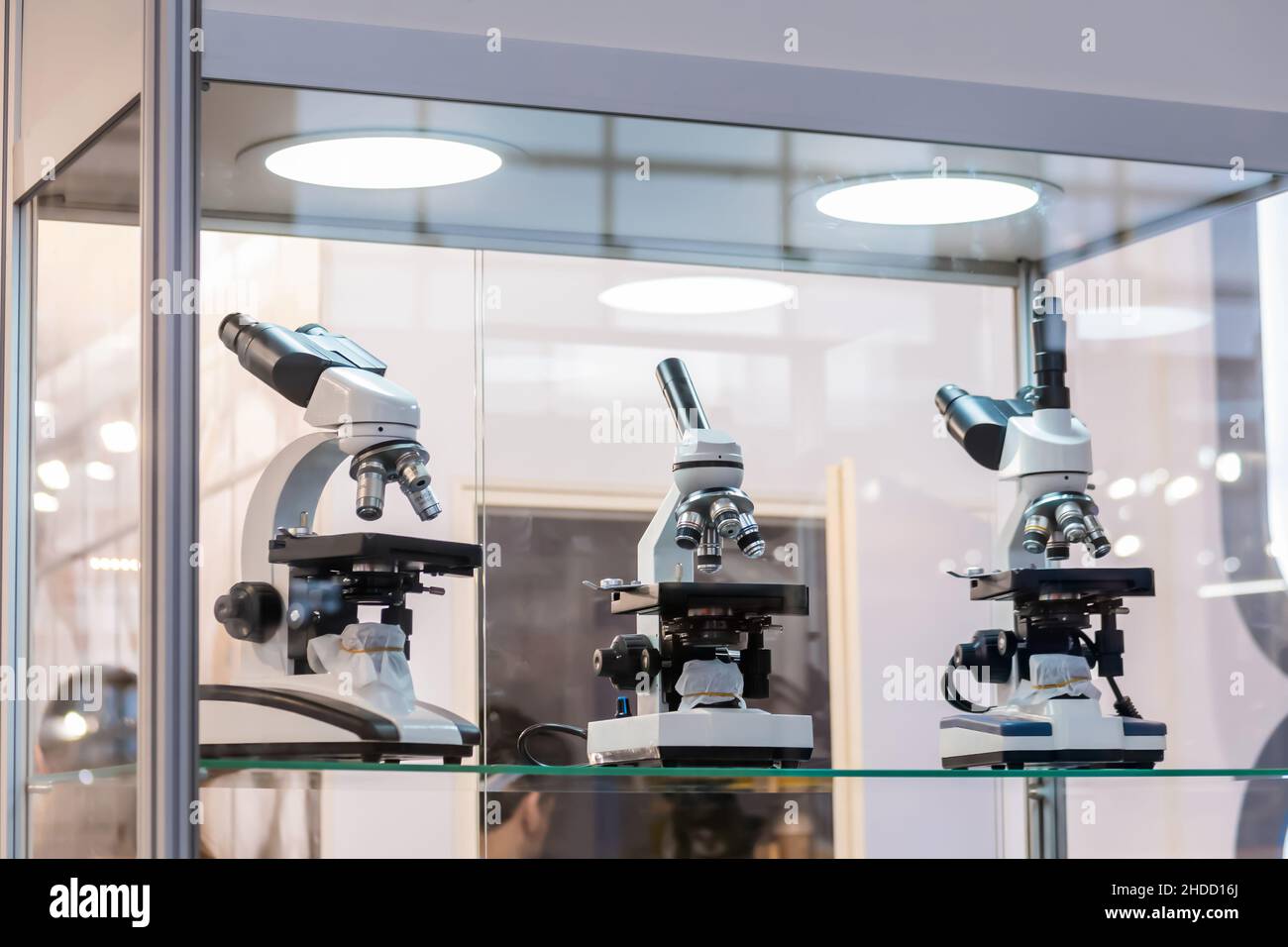 Three microscopes in glass showcase at science exhibition - laboratory ...