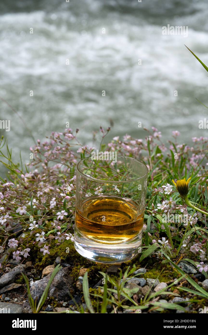 Glass of strong scotch single malt whisky with fast flowing mountain ...