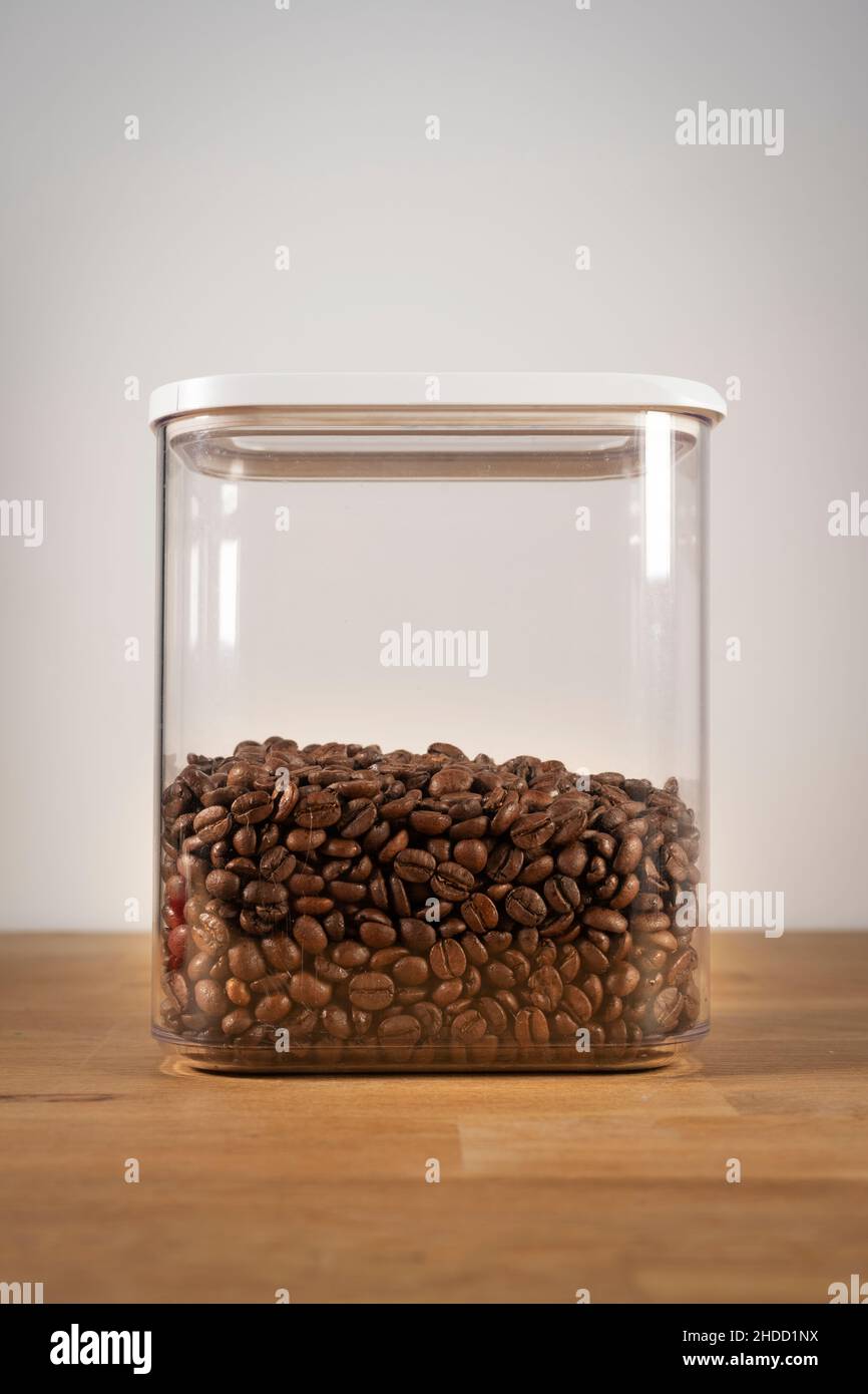 Freshly roasted coffee beans in airtight plastic container on wood ...