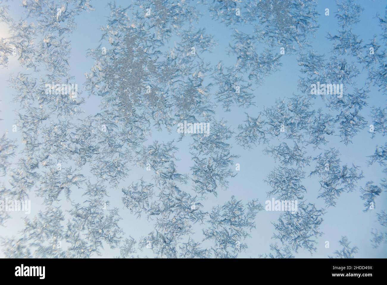 Natural frost pattern on glass window close up with blue winter sky ...