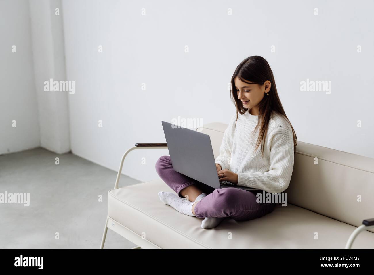 Cute girl sitting on sofa with laptop Stock Photo - Alamy