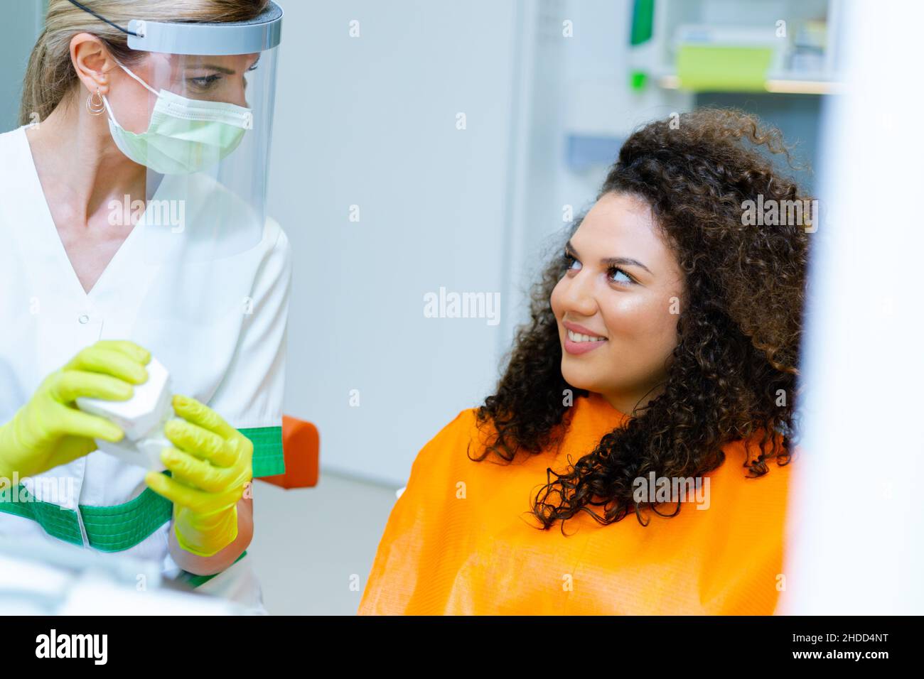 Caucasian female dentist talking to mixed race teenage patient ...