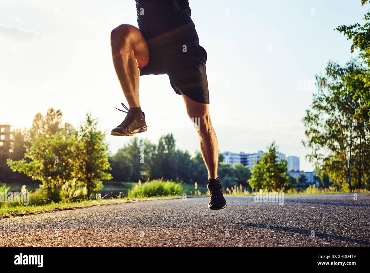 Legs of muscular man jogging. Working out during evening in the city ...
