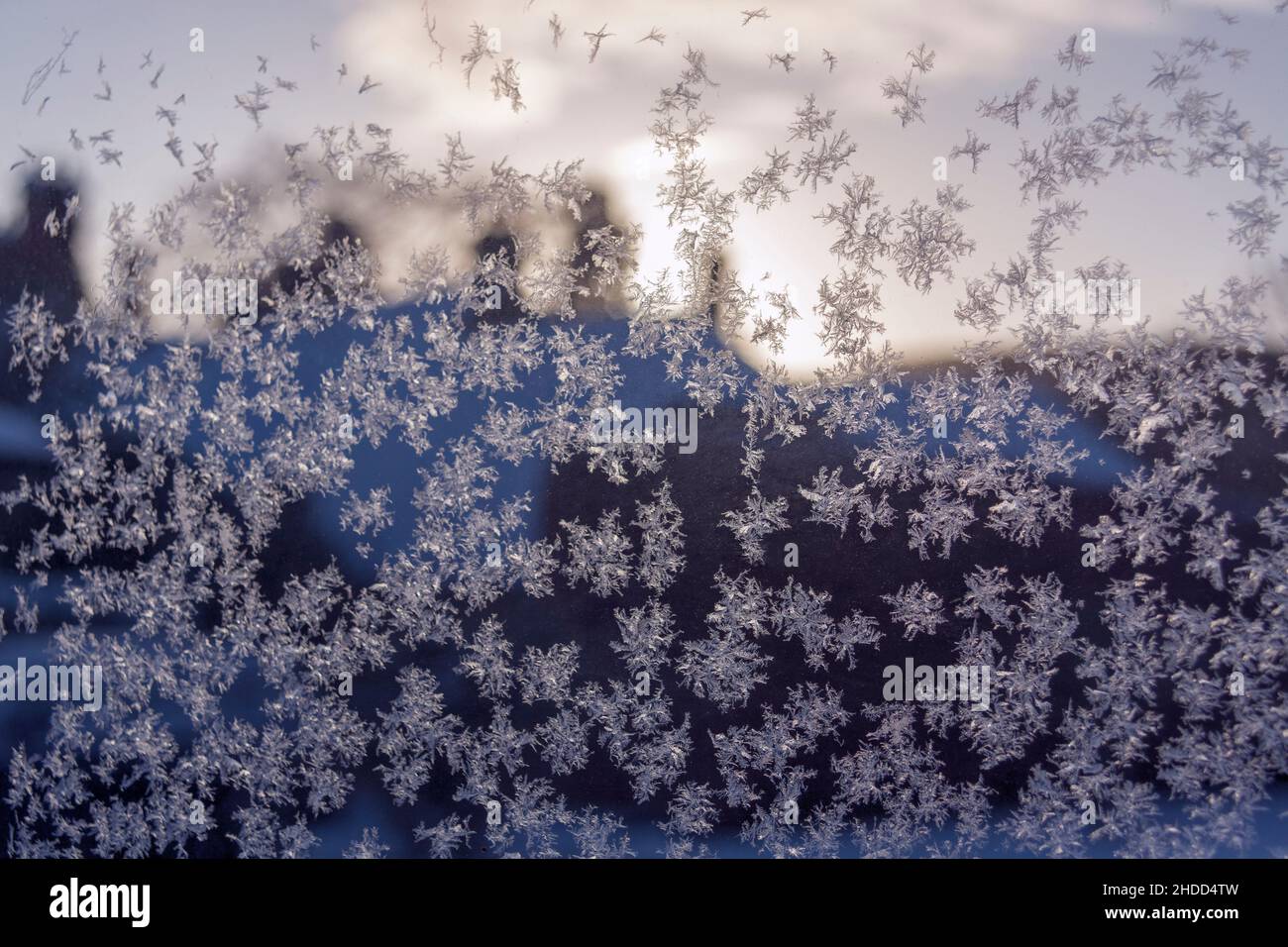 Natural frost pattern on glass window close up with blurred house and ...