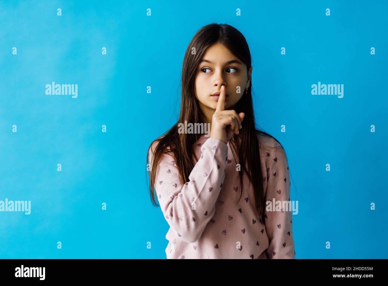 Smiling caucasian little girl wearing blue T-shirt over blue background ...