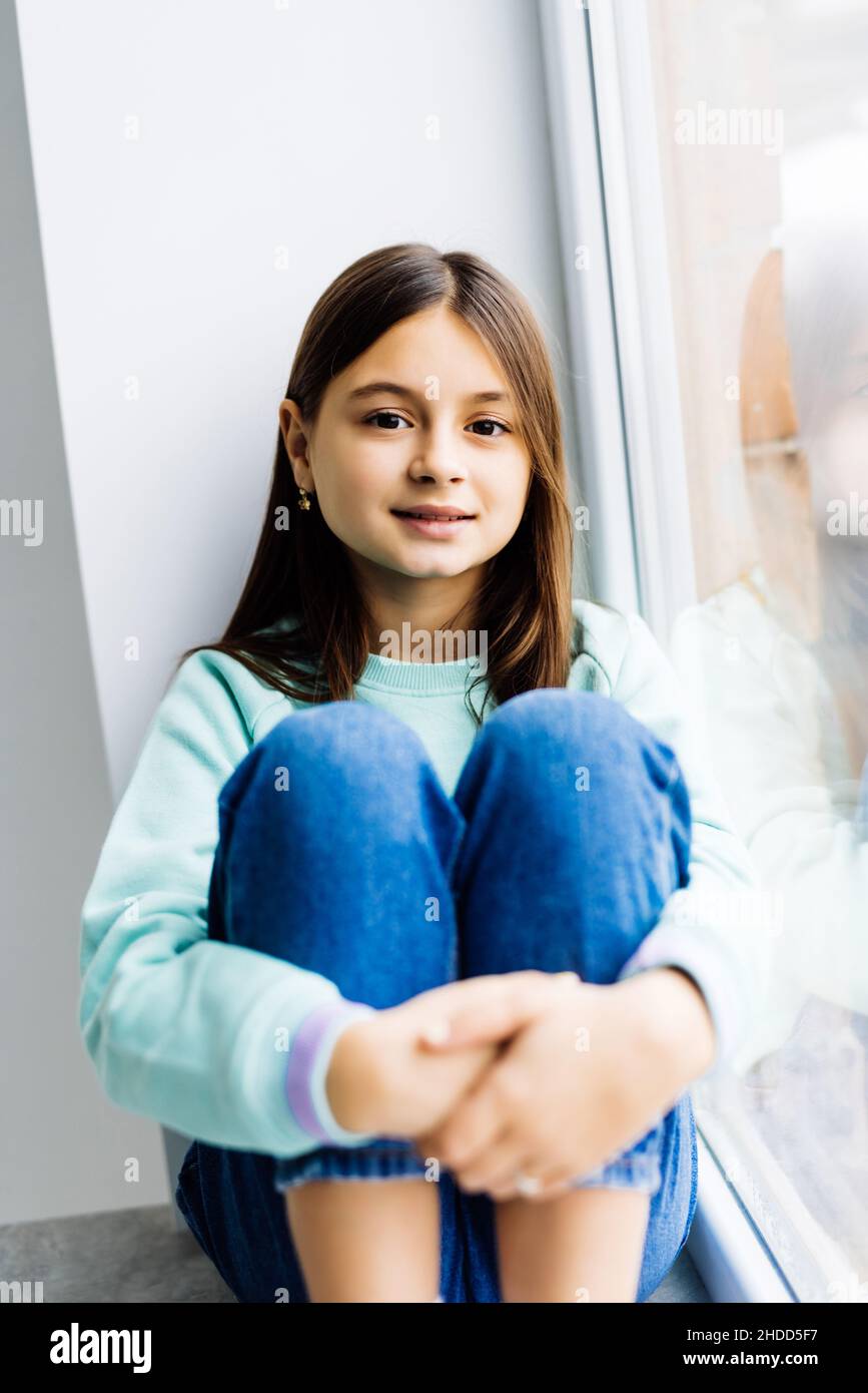 Cute teen girl sitting on the windowsill. T The concept of self ...