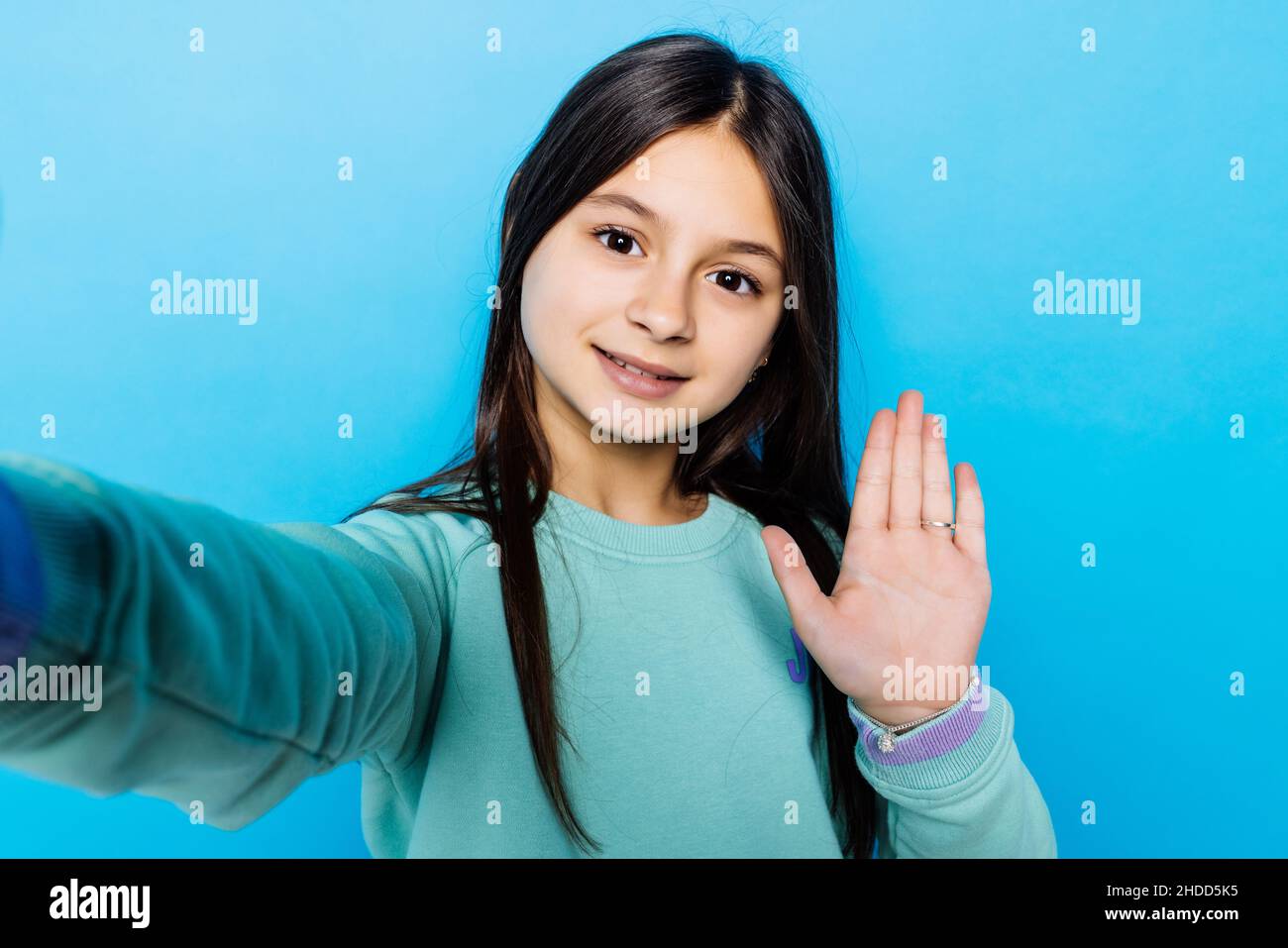 Portrait of happy friendly little girl over blue background taking ...