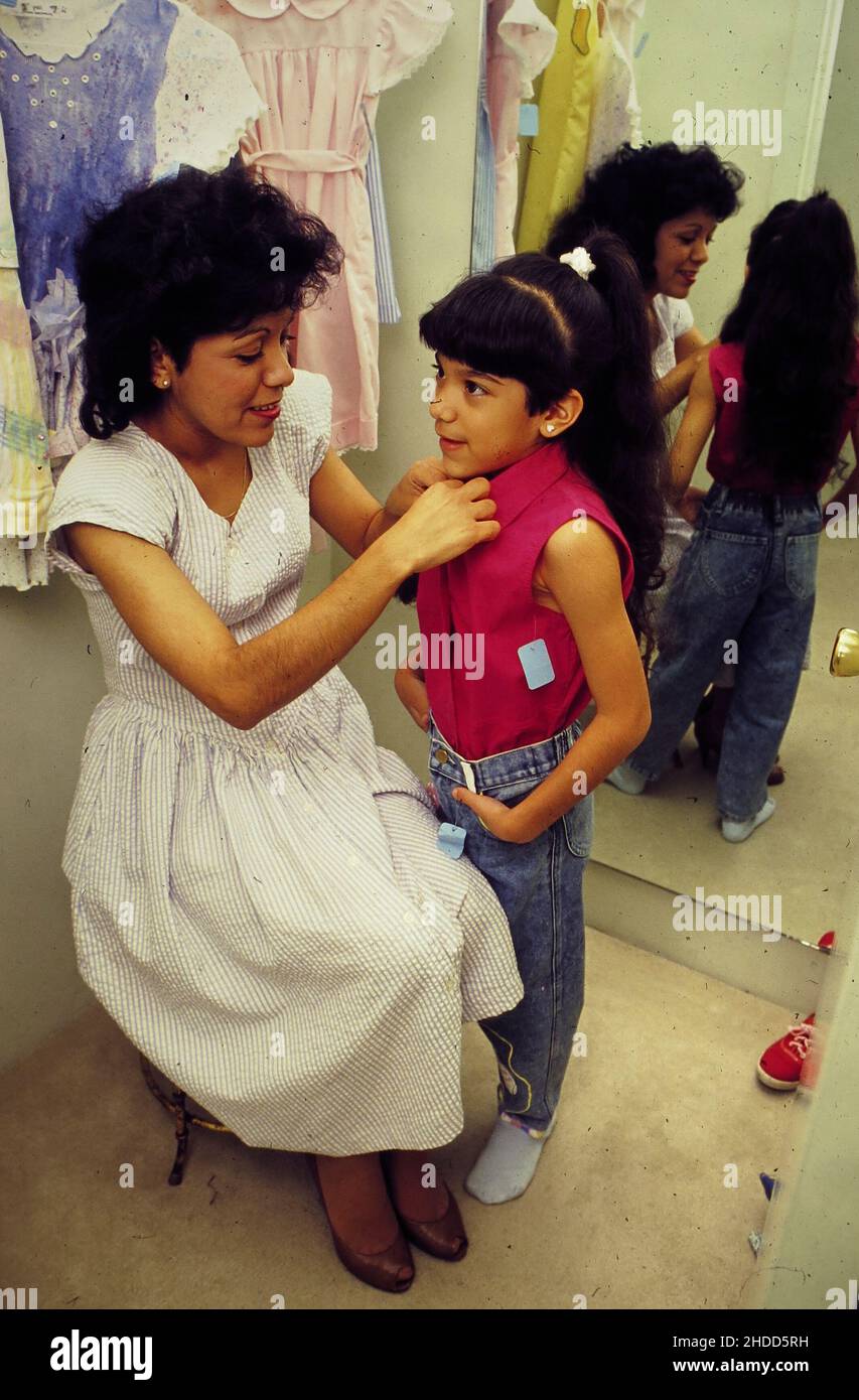 Austin Texas USA, 1990: Hispanic mom helps daughter try on clothes in ...
