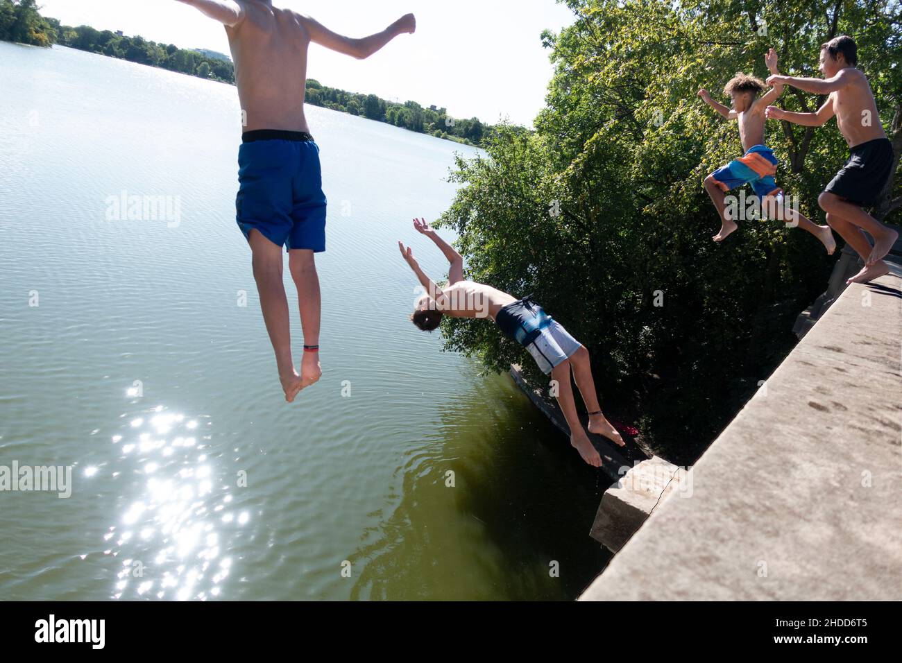 Four young swimmers diving from a bridge into Lake of the Isles ...