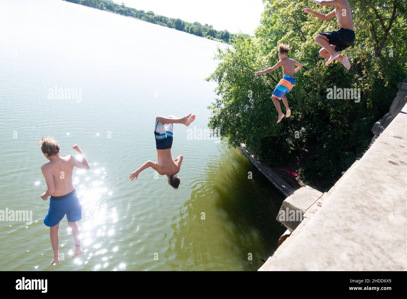 Four young swimmers diving from a bridge into Lake of the Isles ...