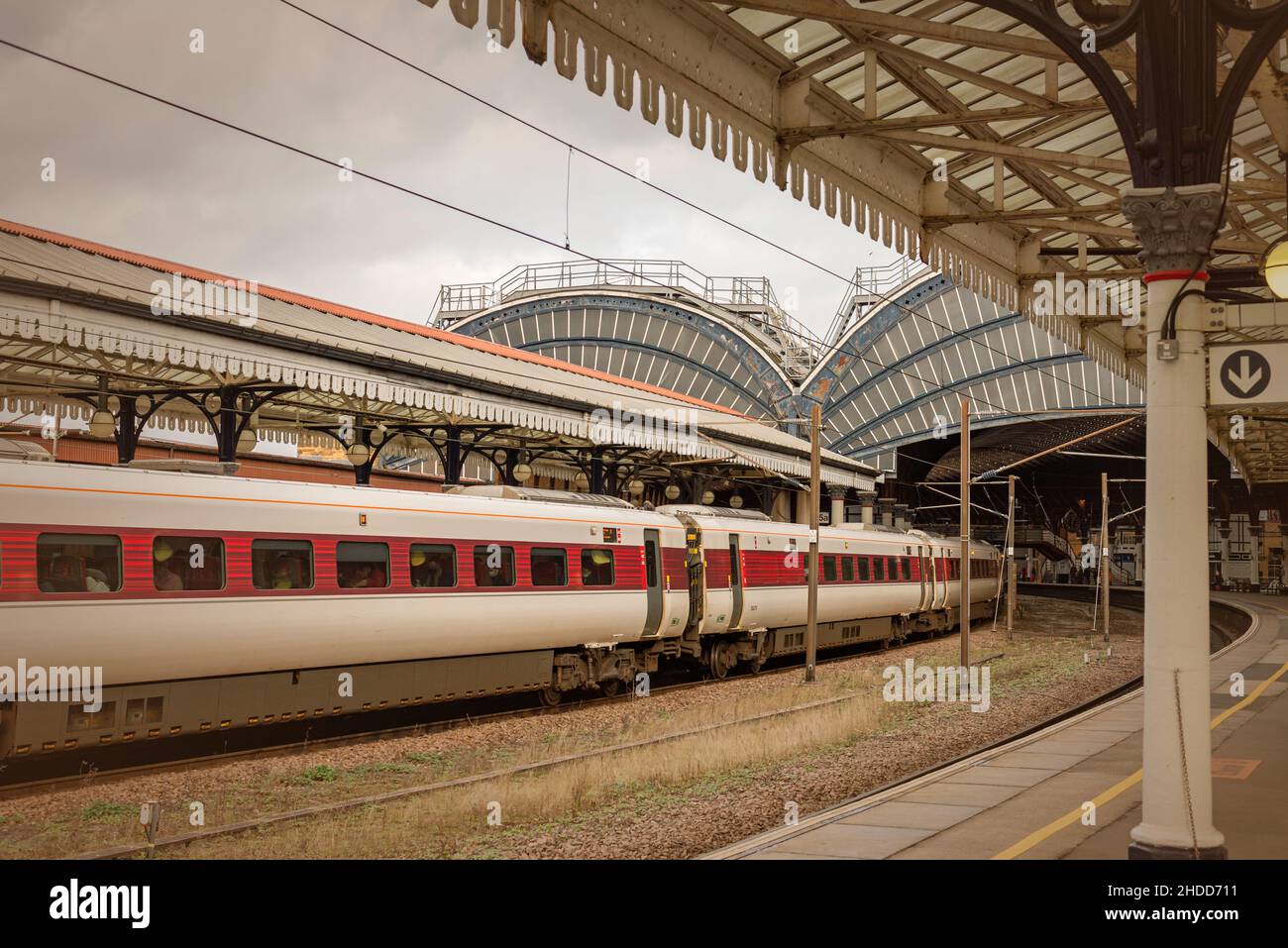Railway station platform with a train alongside. Overhead is an ...