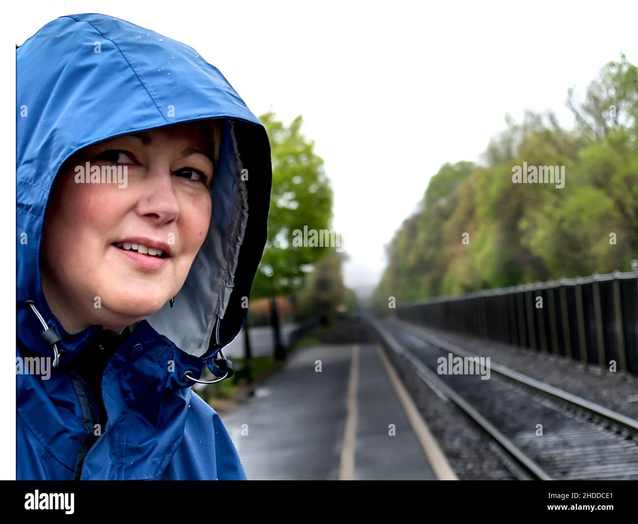 Smiling Mature Woman waiting at train station in the rain Stock Photo ...