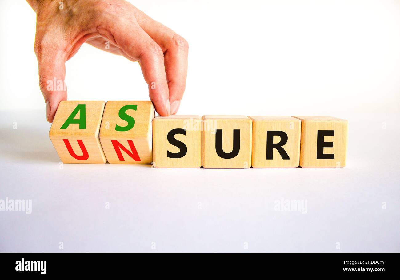 Assure or unsure symbol. Businessman turns wooden cubes and changes the ...