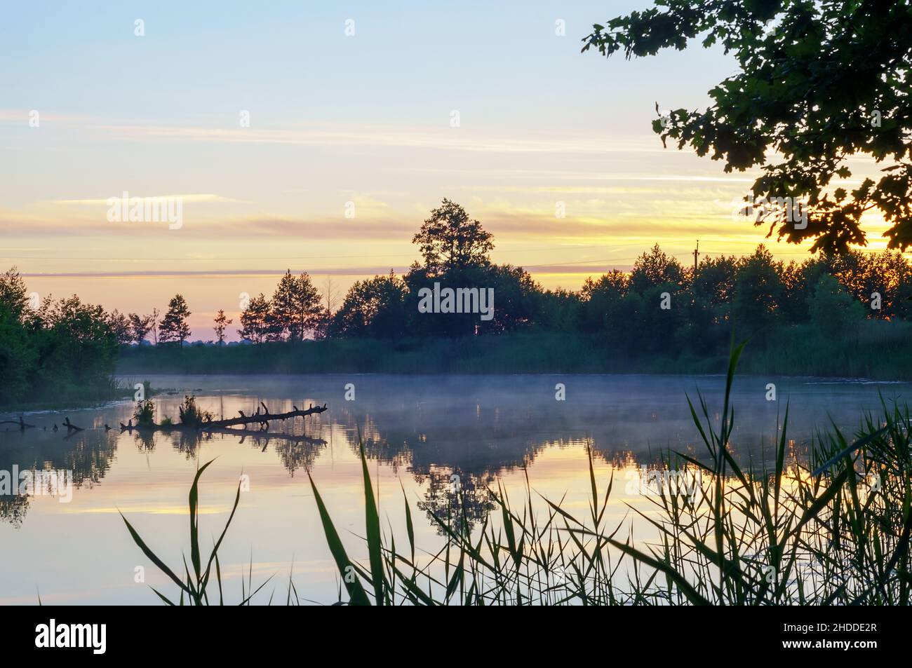 Red sky in the sunset light. Sunset over a pond. Reflection of sunlight ...