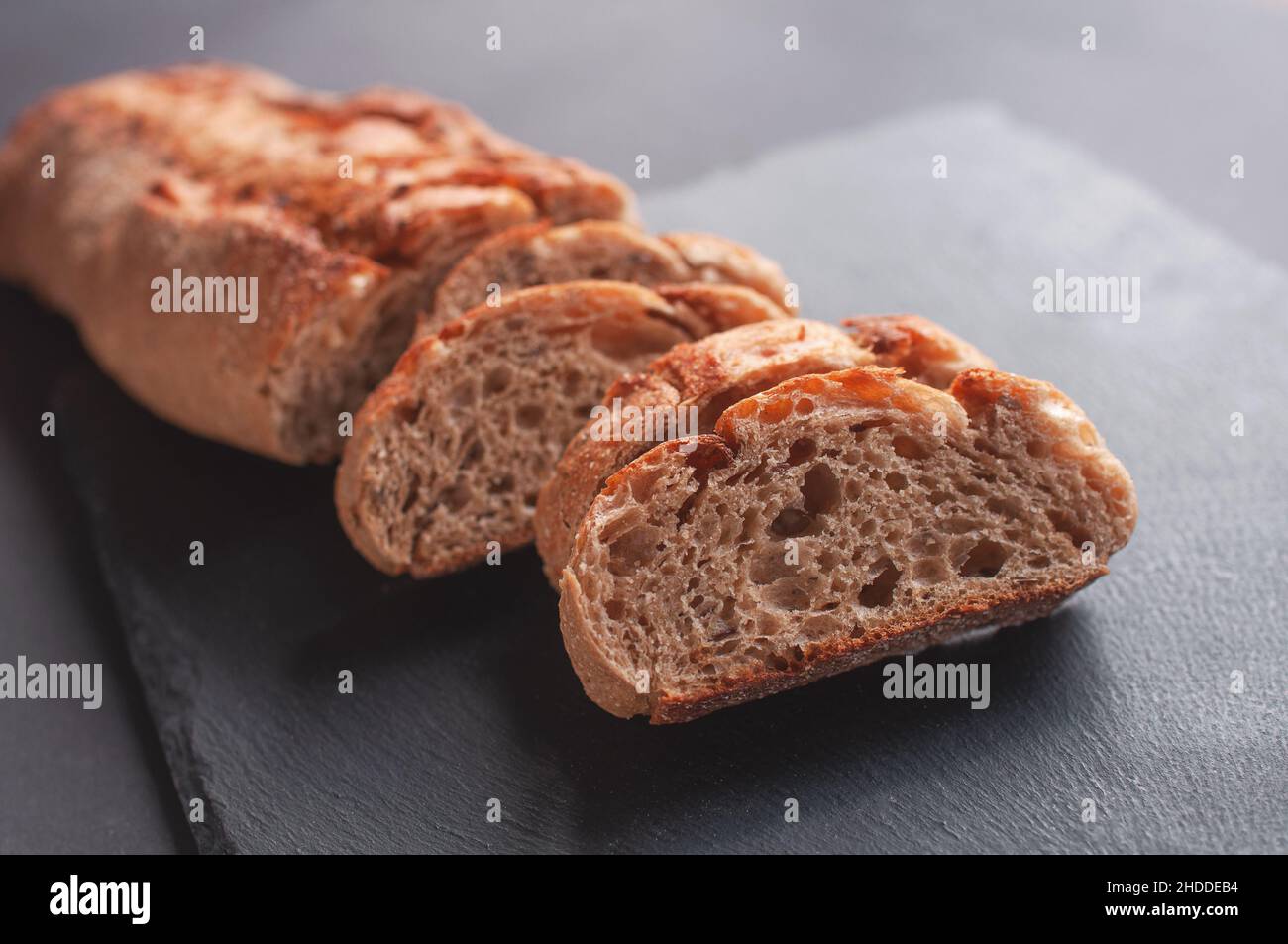 Rustic bread, beautiful golden crust, sliced bread lying on black board ...