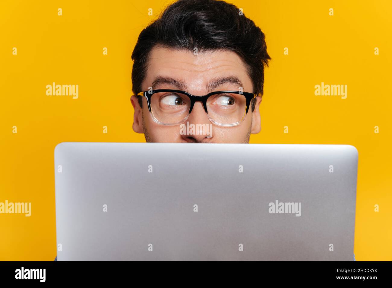 Amazed excited caucasian young adult guy with glasses peeking out from ...