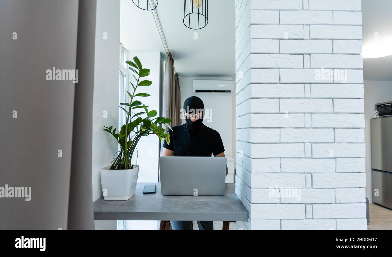 hacker in black balaclava on a laptop Stock Photo - Alamy