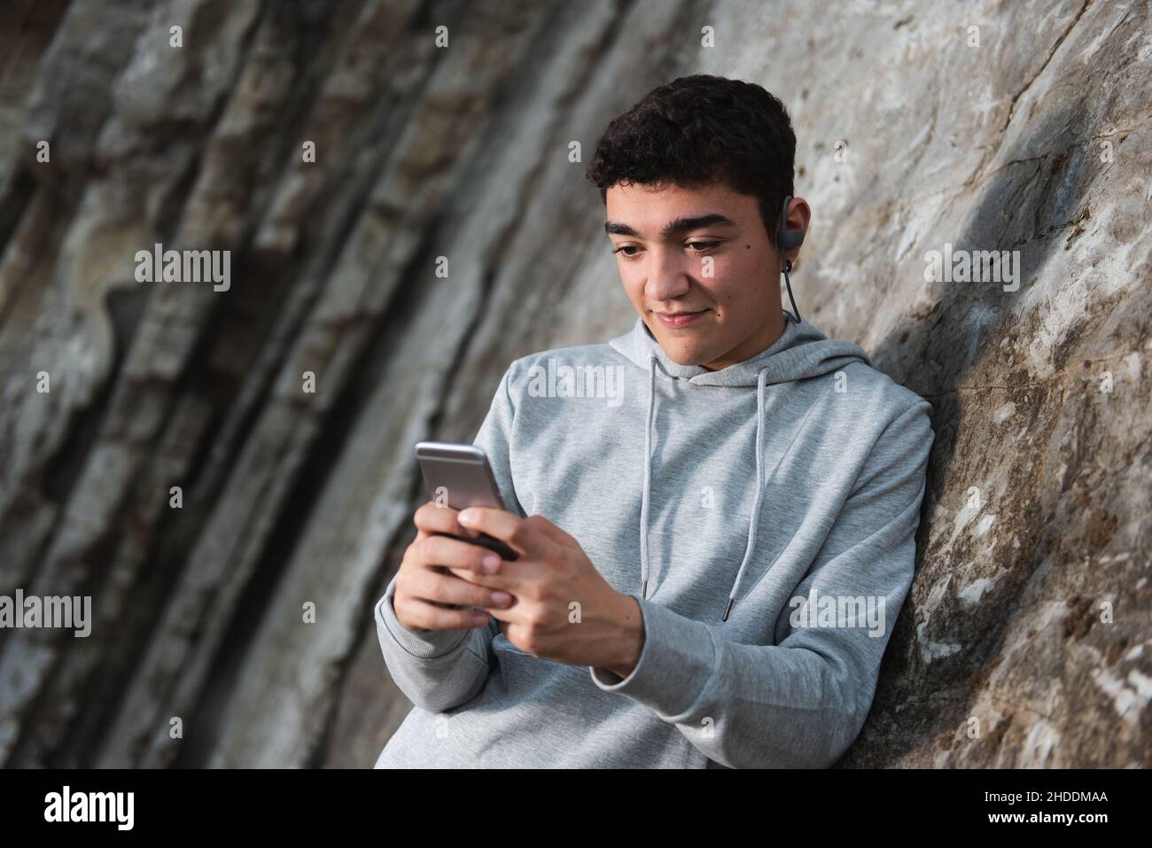 Hispanic generation z boy using cell phone outdoors against wall Stock ...