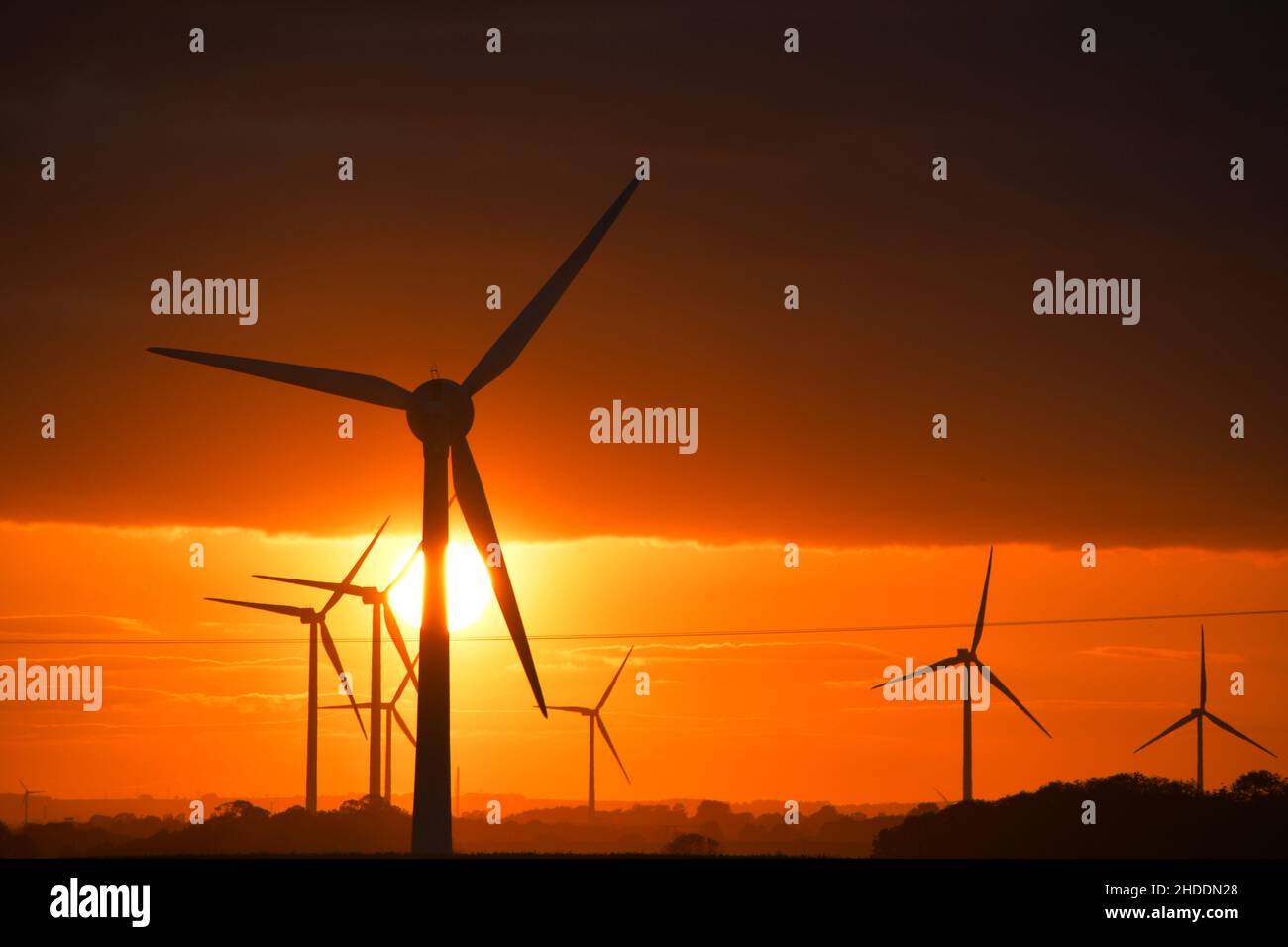 A fiery sunset behind giant UK wind turbines Stock Photo - Alamy