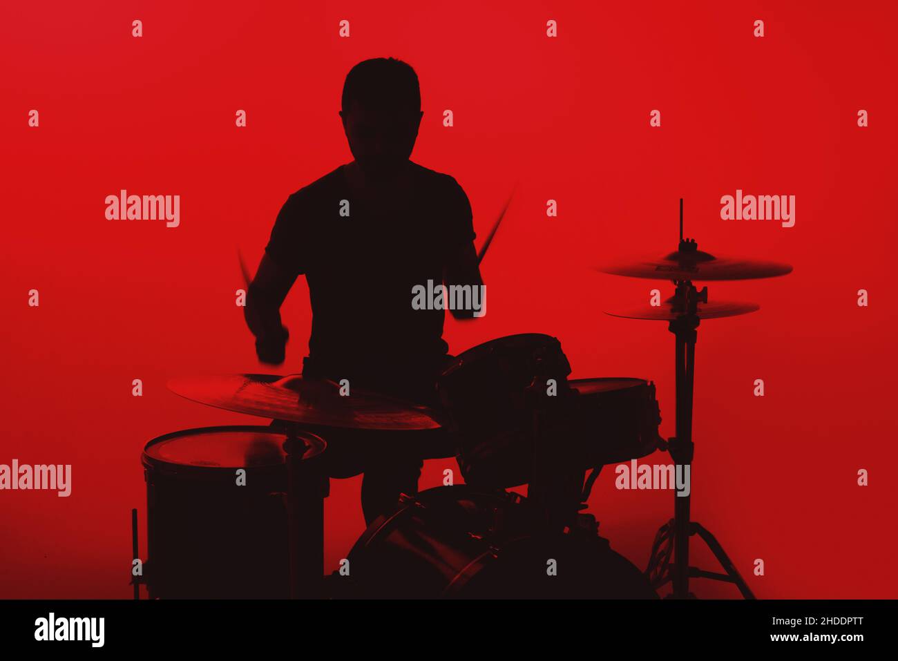Silhouette of a young man playing drums on a red background Stock Photo ...