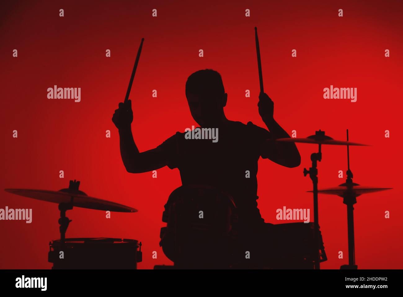 Silhouette of a young man playing drums on a red background Stock Photo ...