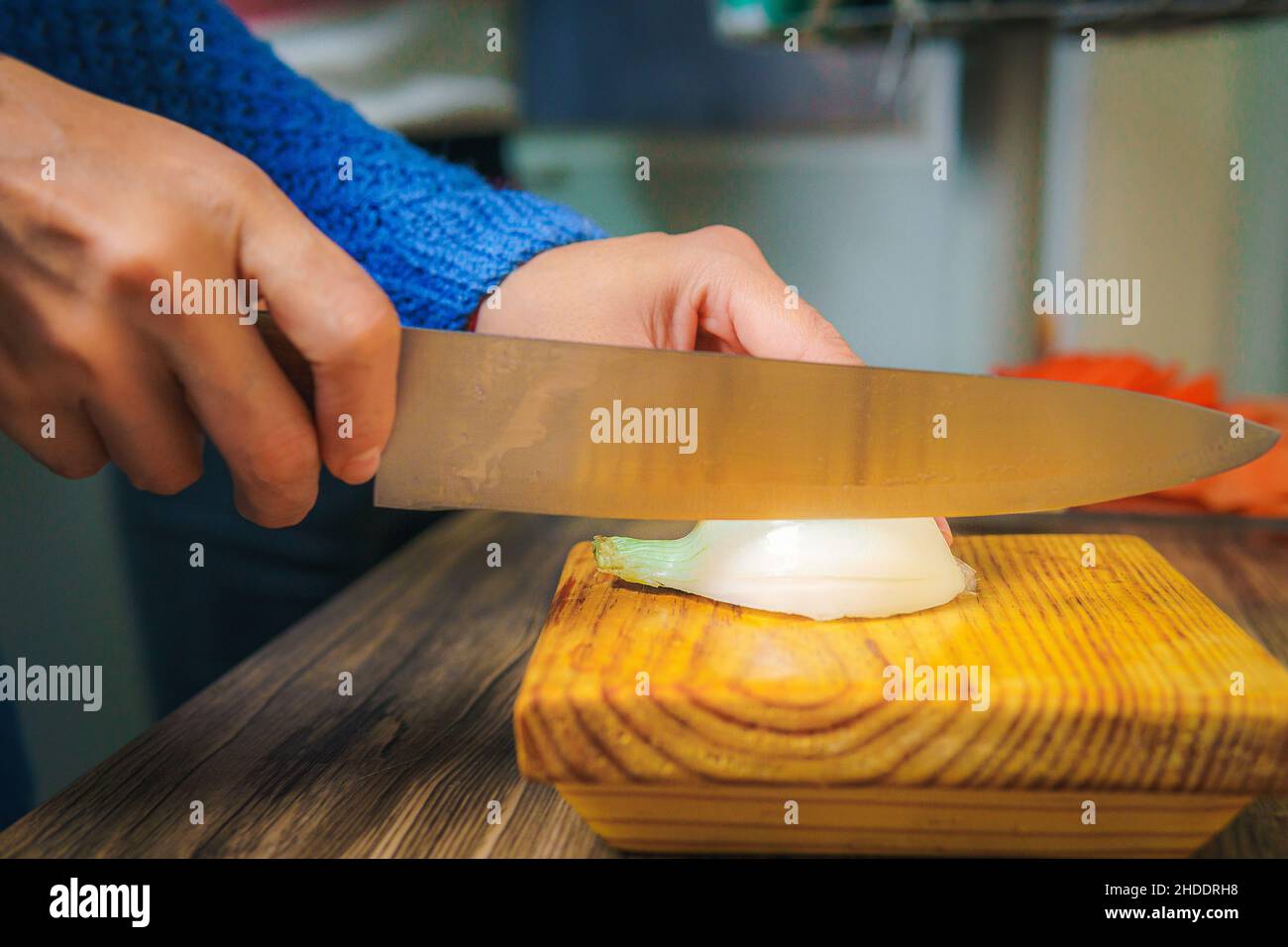 On the table you can see some hands cutting with a chef's knife a white ...