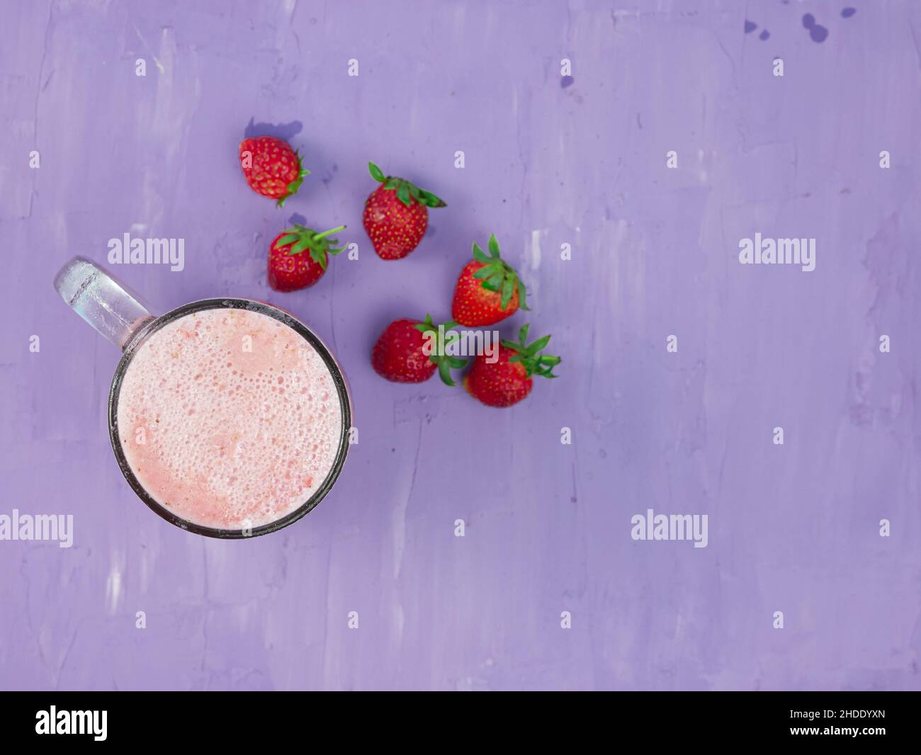 top view of strawberry milkshake juice in glass and some strawberries ...
