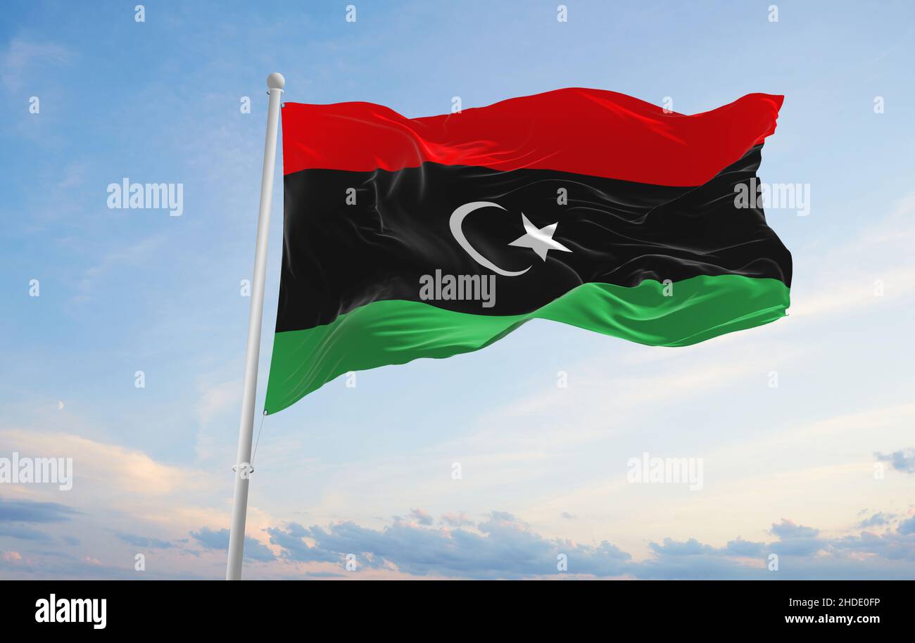 official flag of Libya at cloudy sky background on sunset, panoramic ...