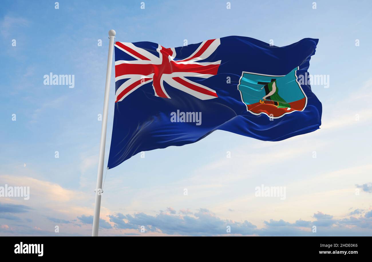 official flag of Montserrat at cloudy sky background on sunset ...