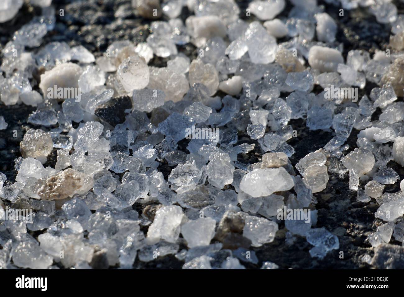 Macro view of ice and snow melt salt crystals on an asphalt walkway in ...
