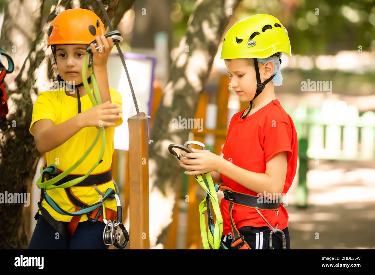 Child in forest adventure park. Kids climb on high rope trail. Agility ...
