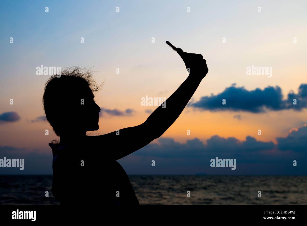 Silhouette picture of woman taking selfie during sunset background ...
