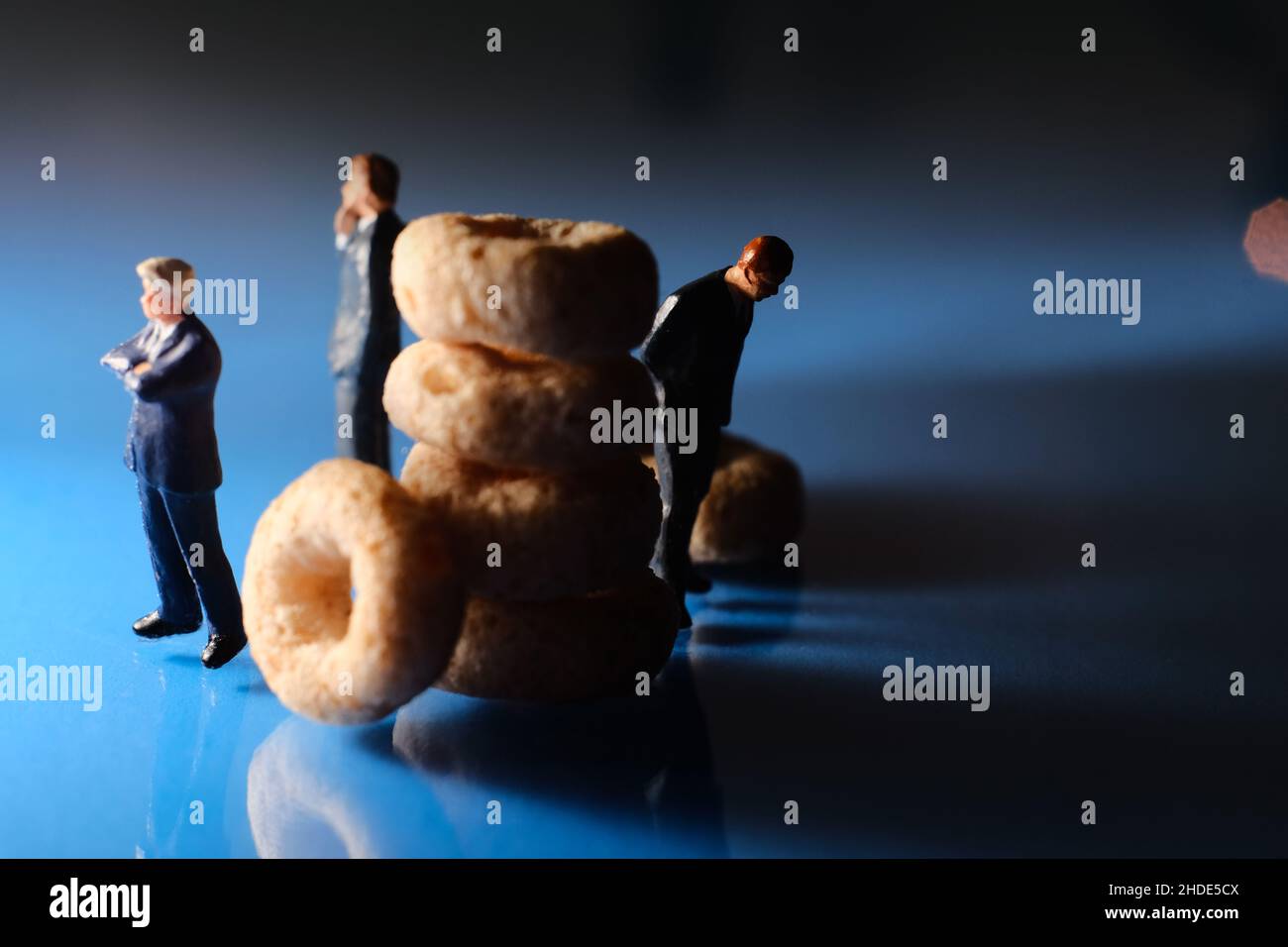 Miniature businessmen inspect toasted oat loop cereal for quality ...