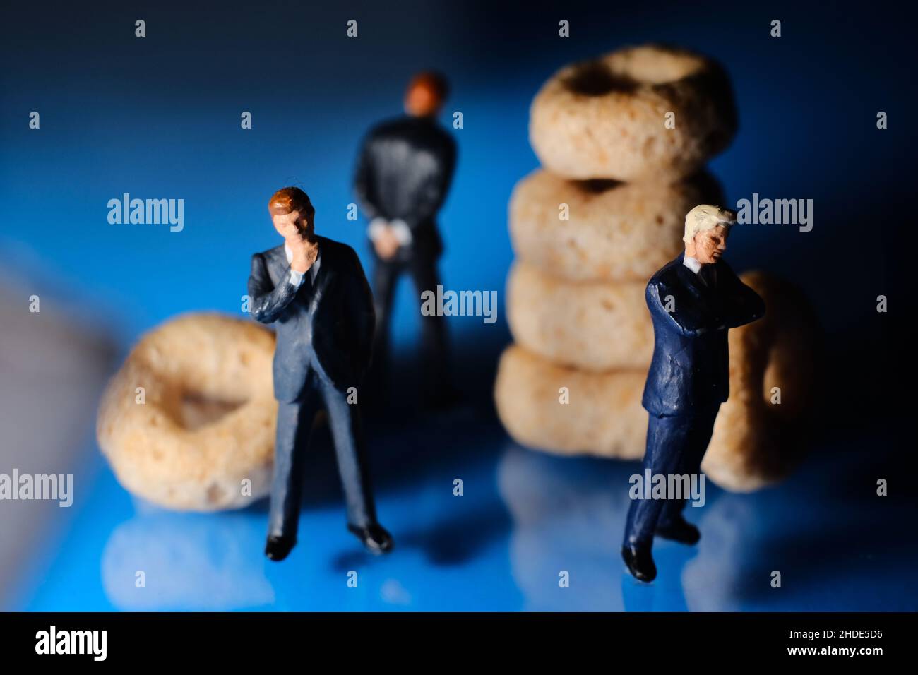 Miniature businessmen inspect toasted oat loop cereal for quality ...