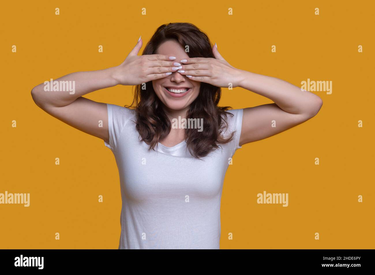 Cheerful female dressed in casual clothes hiding her face Stock Photo ...