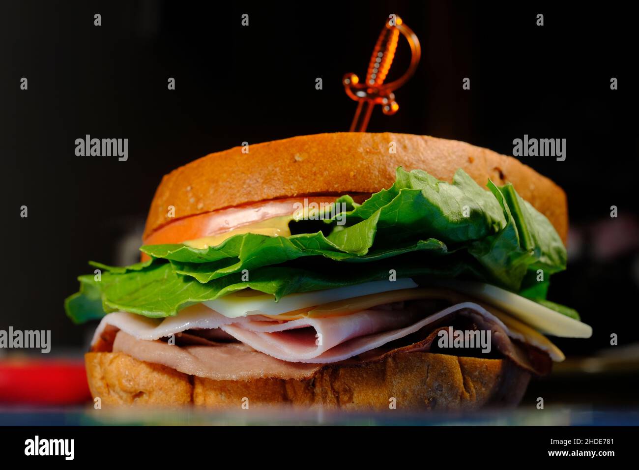 Ham and roast beef sandwich with American cheese and a cocktail sword ...