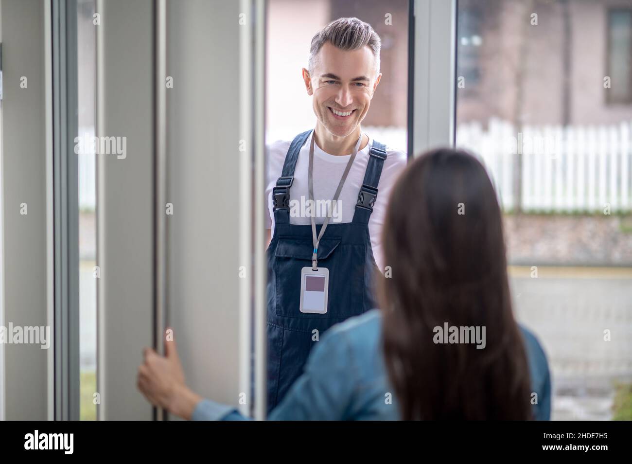 Woman with back to camera opening door to man Stock Photo - Alamy