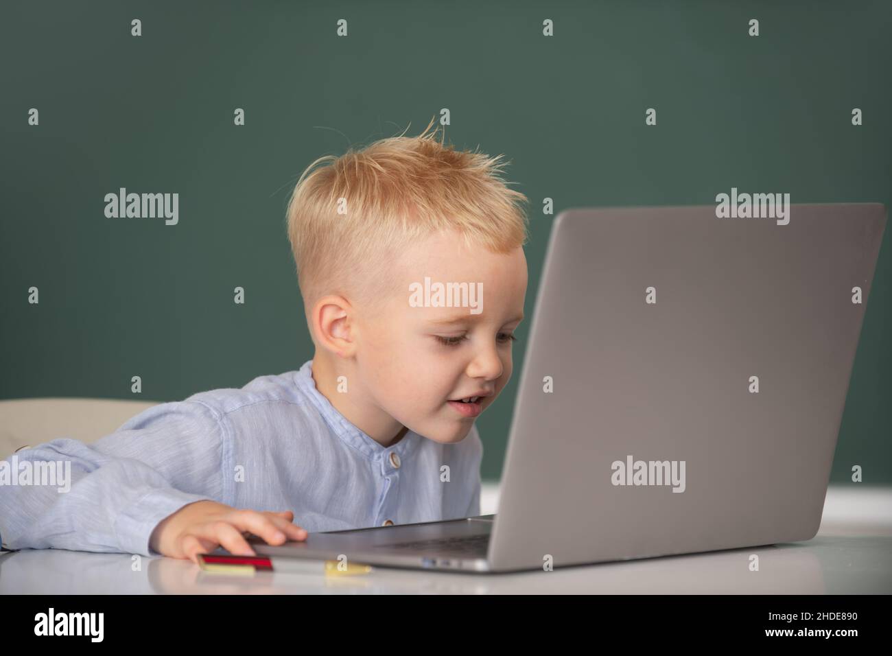 Little student boy using laptop computer in school class. Funny blonde ...
