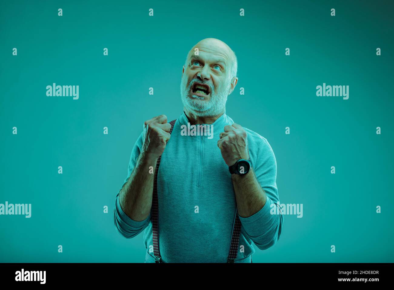 Angry frustrated senior man balling his fists and gnashing his teeth as ...