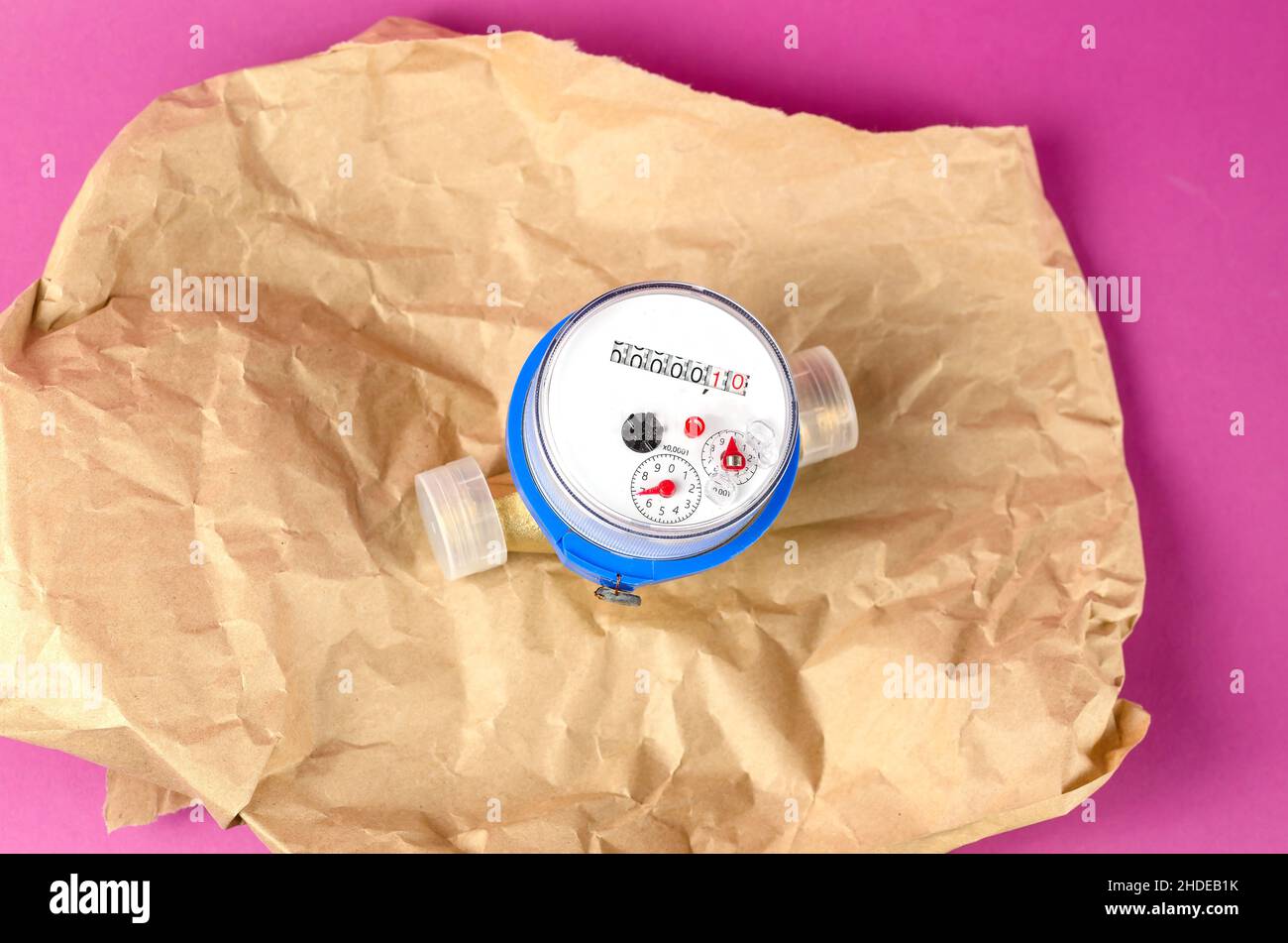 New water meter in wrap-around paper opposite magenta background. A ...