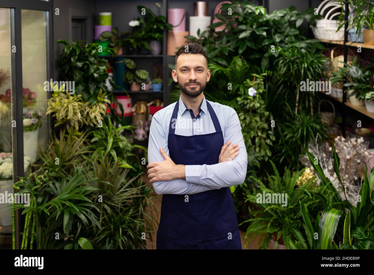 a florist man in a boutique of bouquets and flowers stands with a smile ...