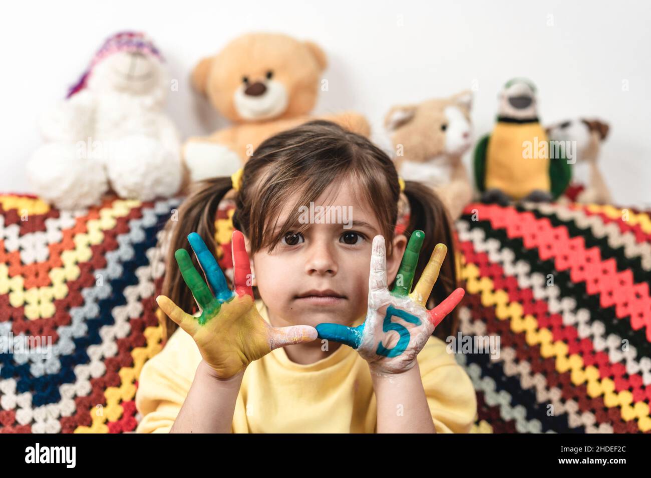 Serious little girl with the five number painted on the hand looking ...