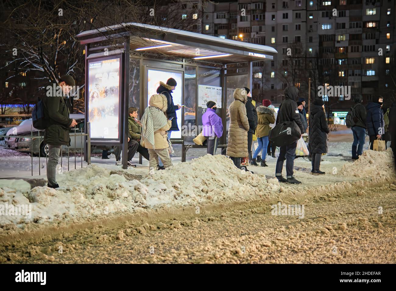 People are waiting for the bus at the bus stop winter night snow on the ...
