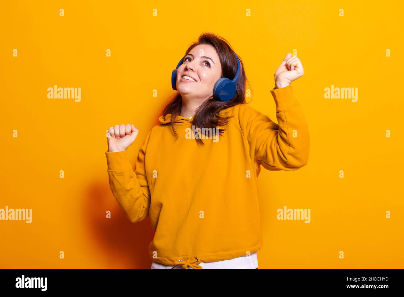 Playful person dancing and listening to music on headset in studio ...