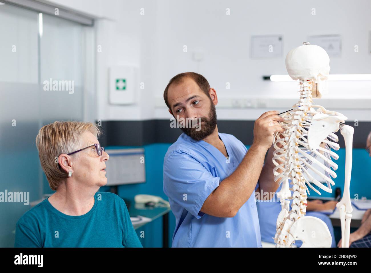 Woman and nurse looking at spinal cord on human skeleton for ...