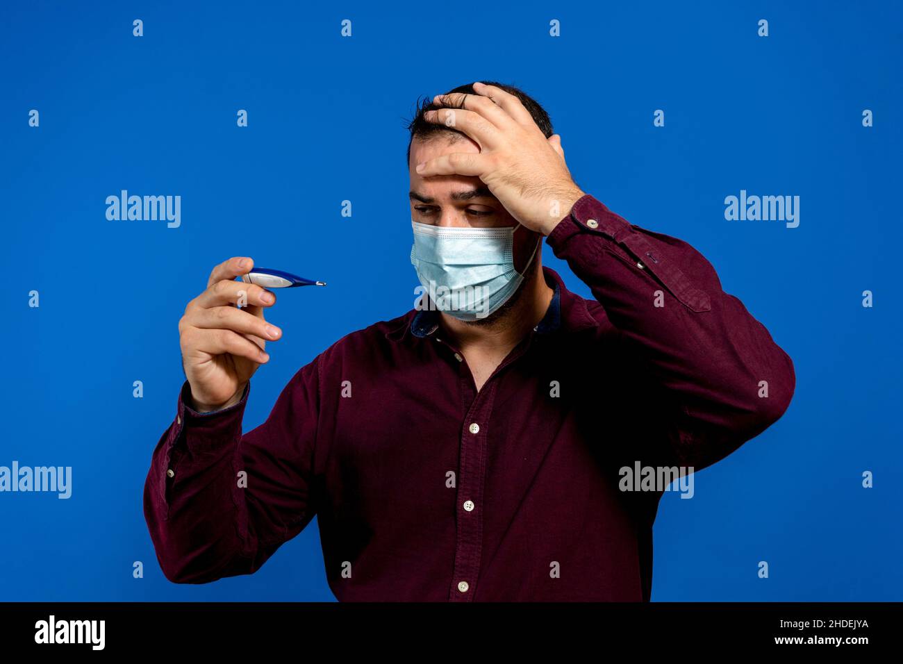Worried man in face mask and office clothes looks at digital ...