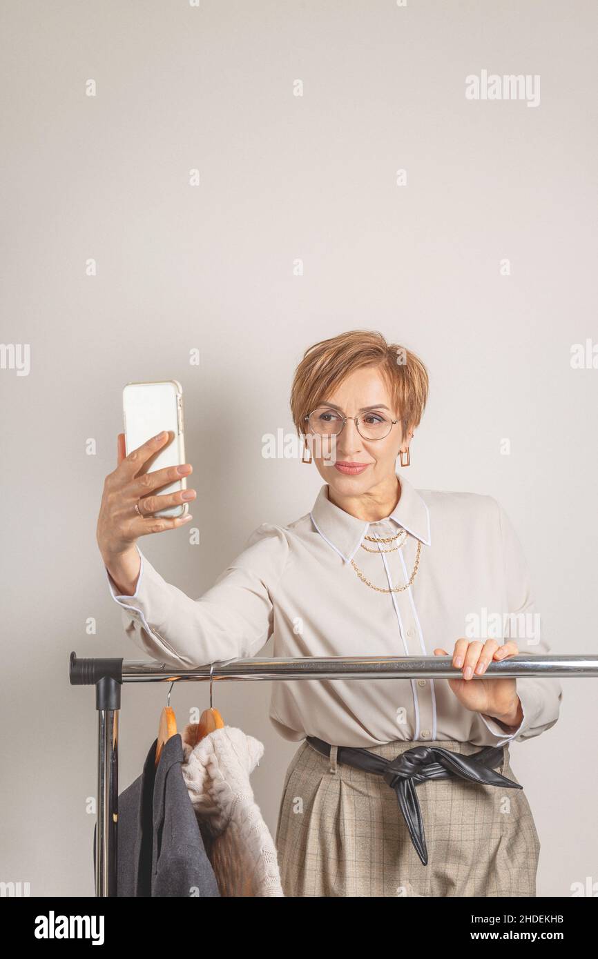 Beautiful baby boomer woman of middle age in glasses smile and makes ...